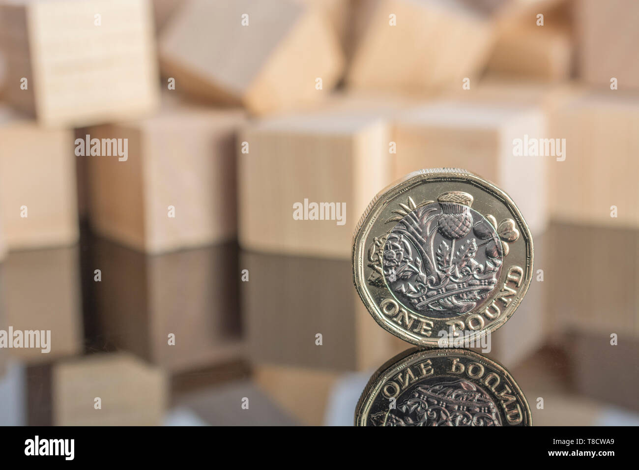 UK New Pound coin on reflective background with scattered wood bricks ...