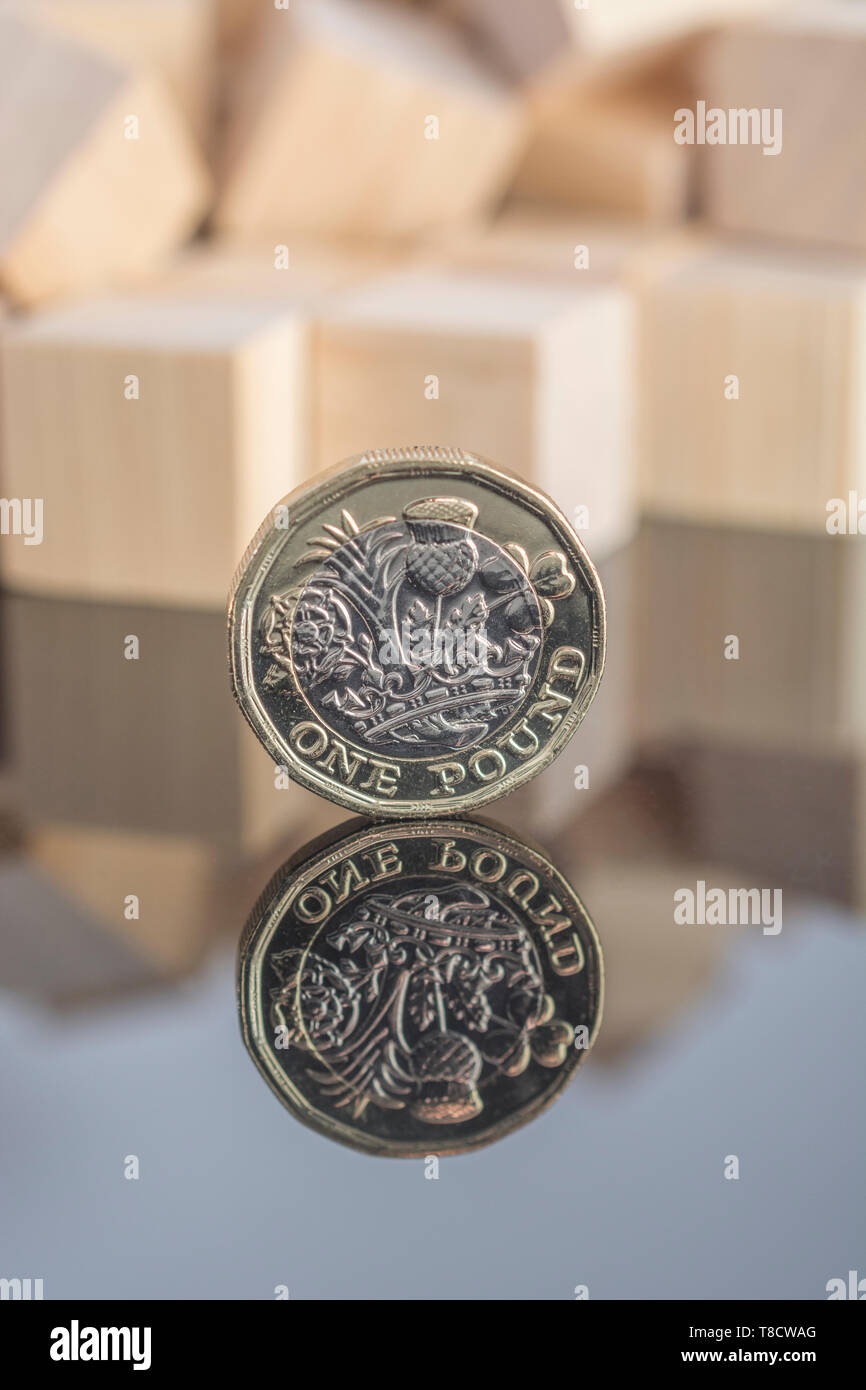 UK New Pound coin on reflective background with scattered wood bricks ...