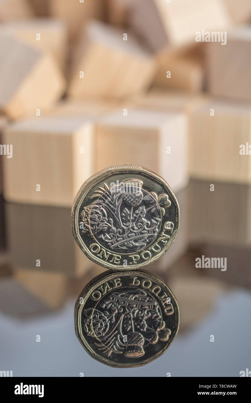UK New Pound coin on reflective background with scattered wood bricks ...
