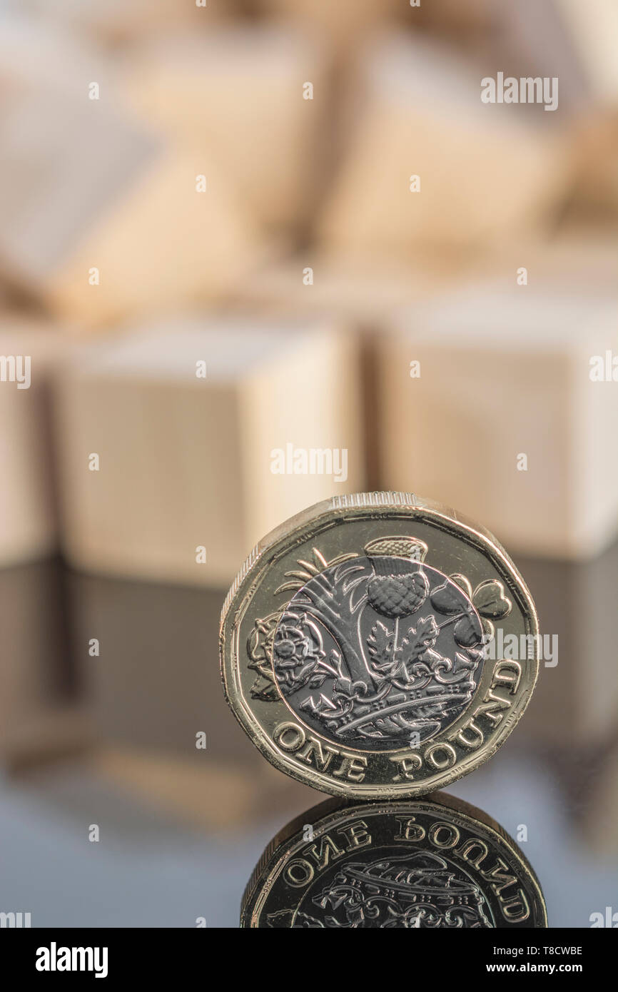 UK New Pound coin on reflective background with scattered wood bricks ...