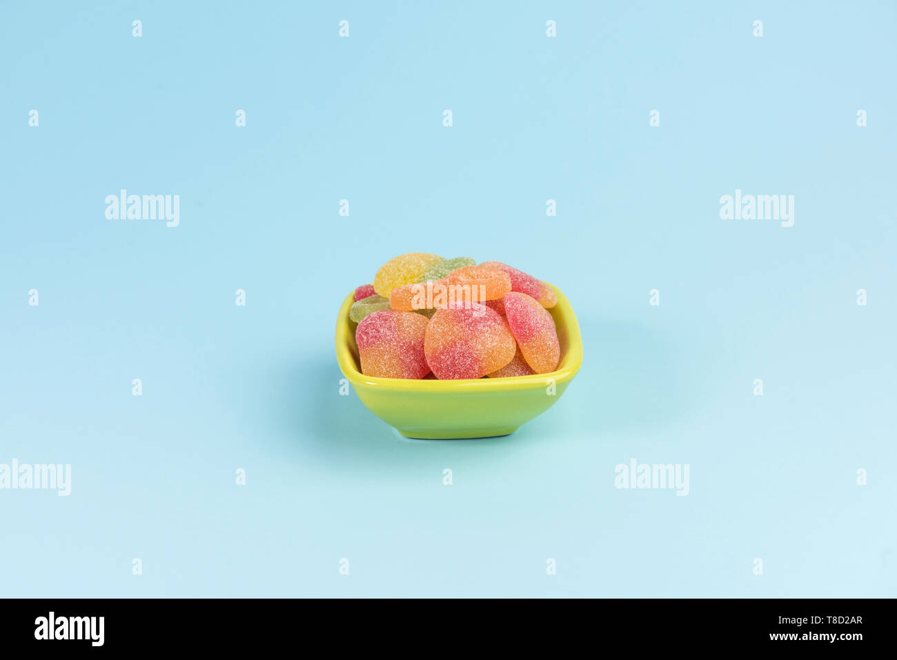 Small bowl with gummy candies isolated on blue background Stock Photo ...