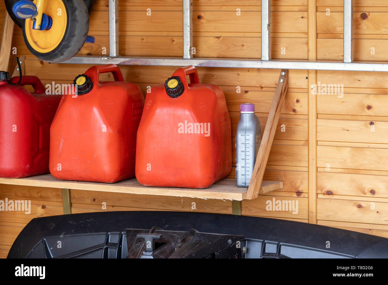Garage corner with three red plastic fuel cans , staircase and snow ...