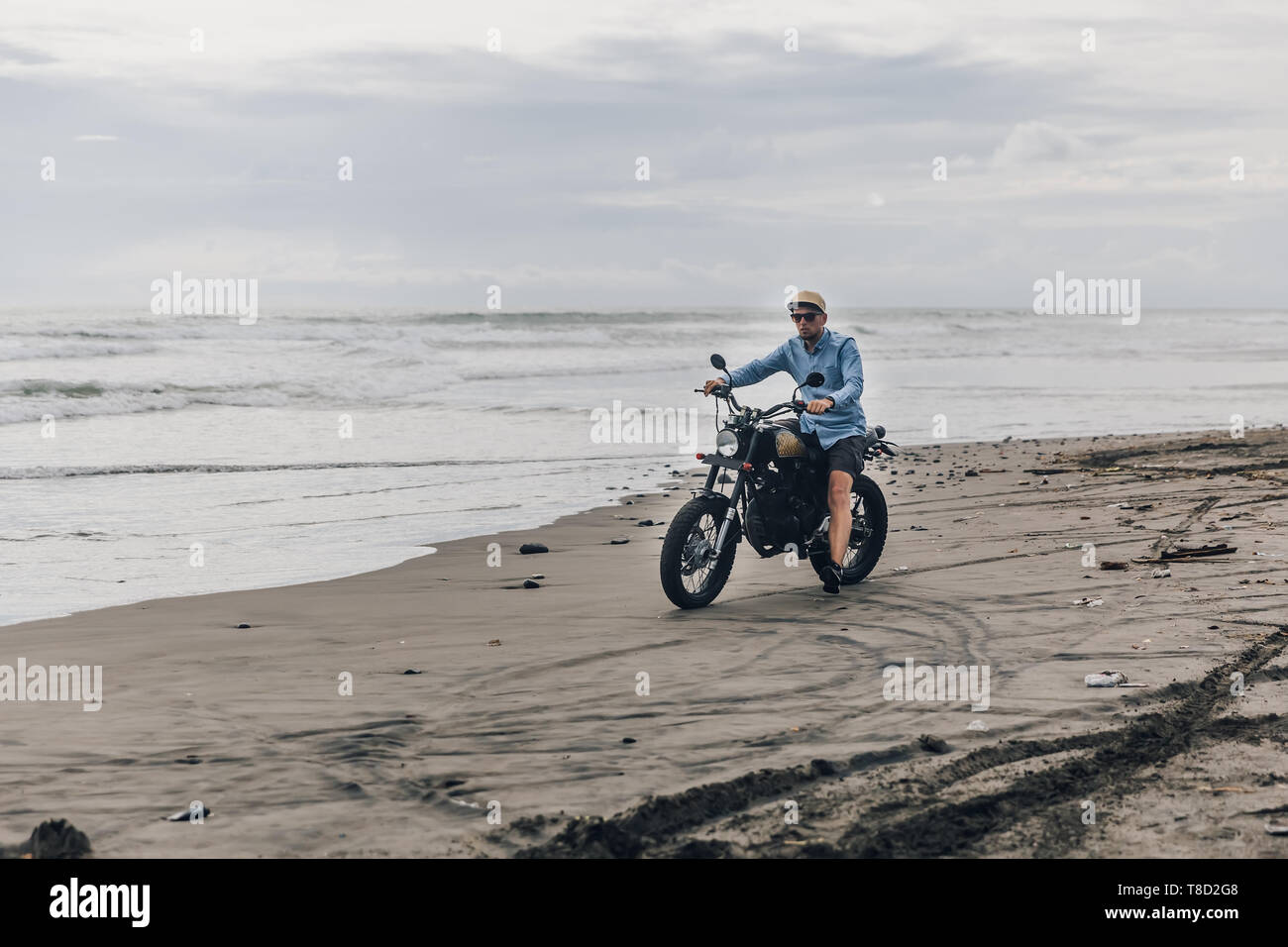Man in cap riding motorcycle on beach. Moto cross dirtbiker on beach ...