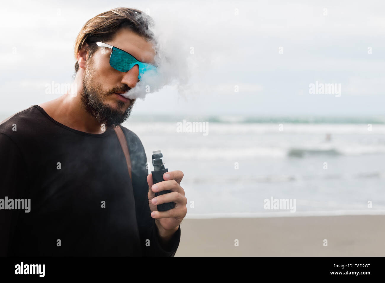 Man With Beard And Sunglasses Smoking Electronic Sigarette Outdoor On