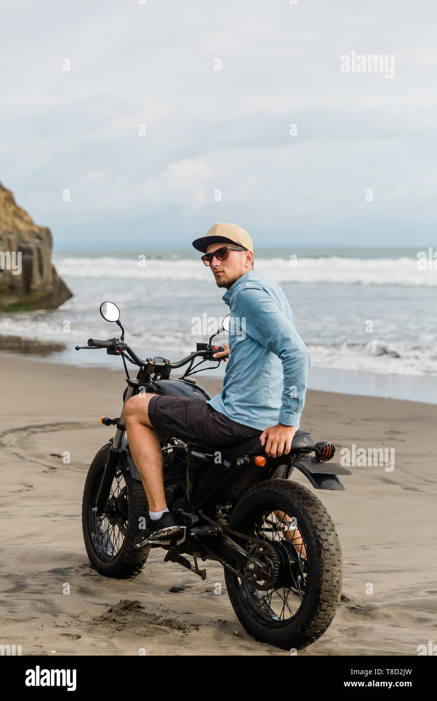 Man in cap riding motorcycle on beach. Moto cross dirtbiker on beach ...