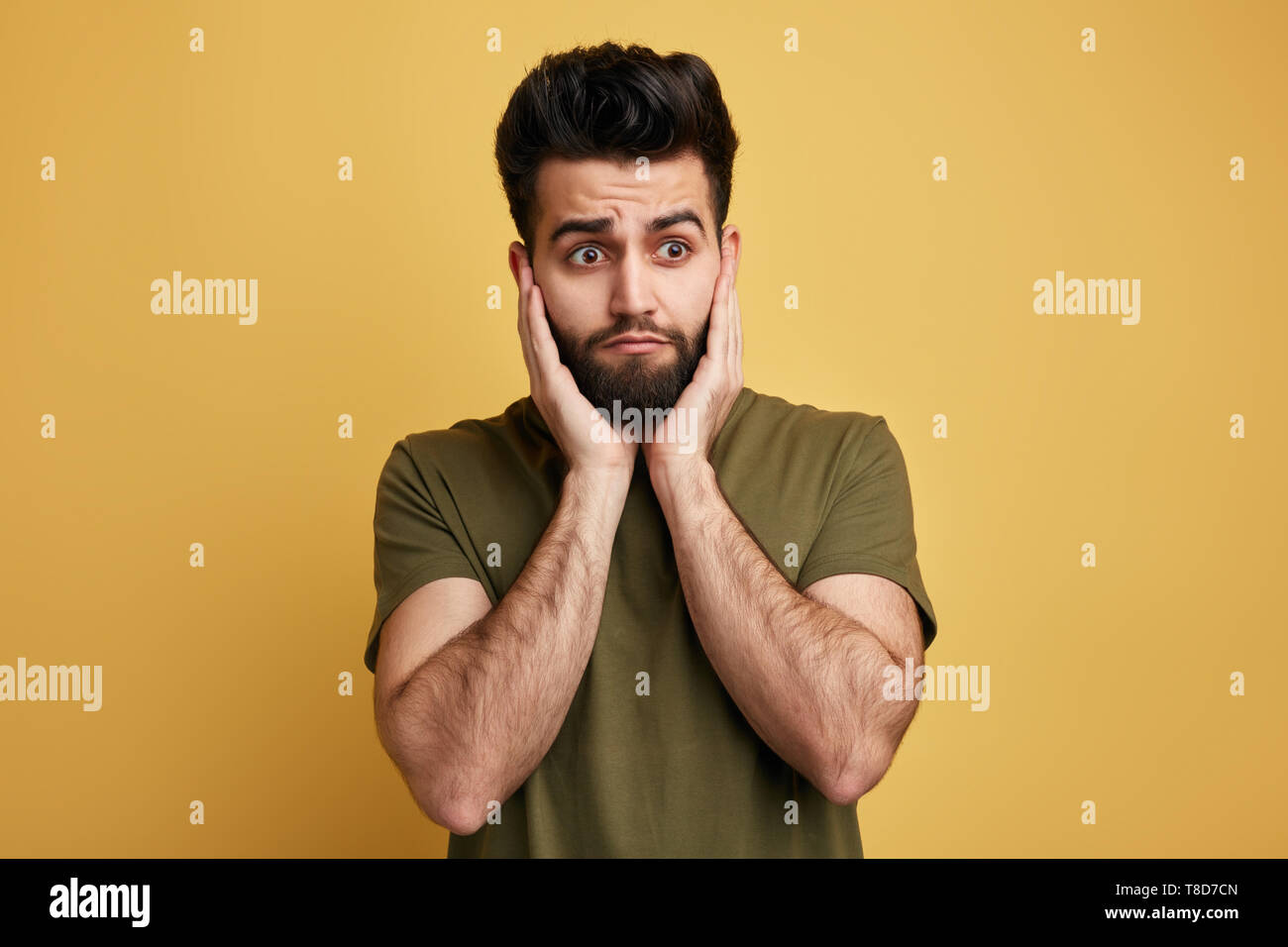 scared handsome man hears negative news, keeps palms on cheeks ...