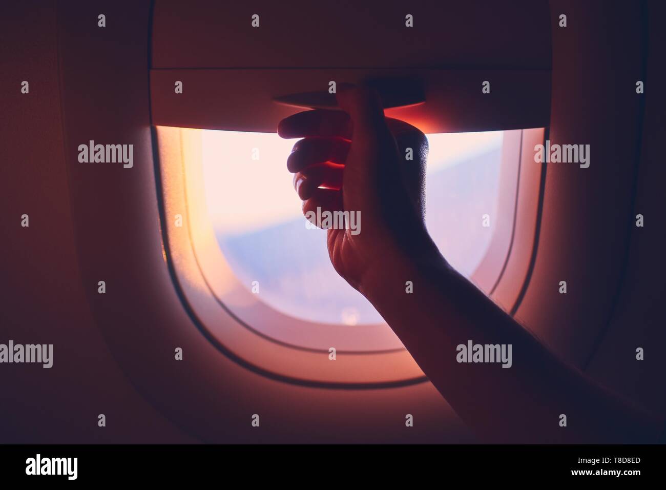 Travel by airplane. Hand pulling down or up window blinds during flight ...