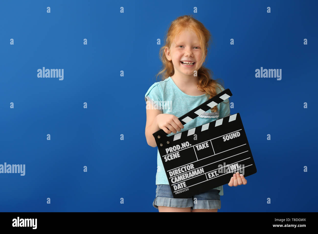 Cute little girl with clapper board on color background Stock Photo - Alamy