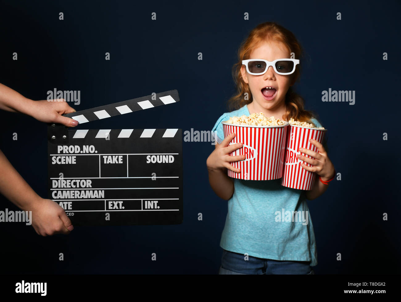 Female hands with clapper board and cute girl holding cups of popcorn ...
