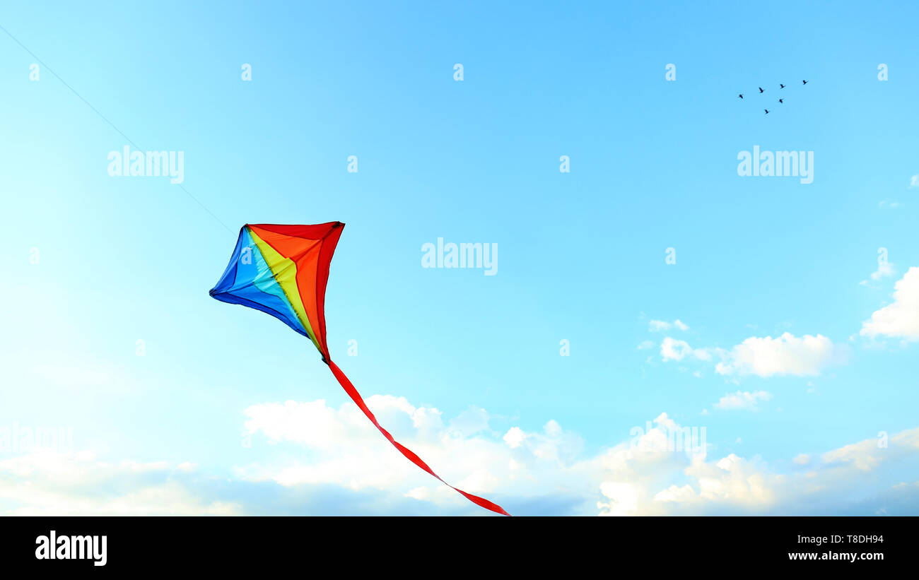 Colorful kite flying in blue sky Stock Photo - Alamy