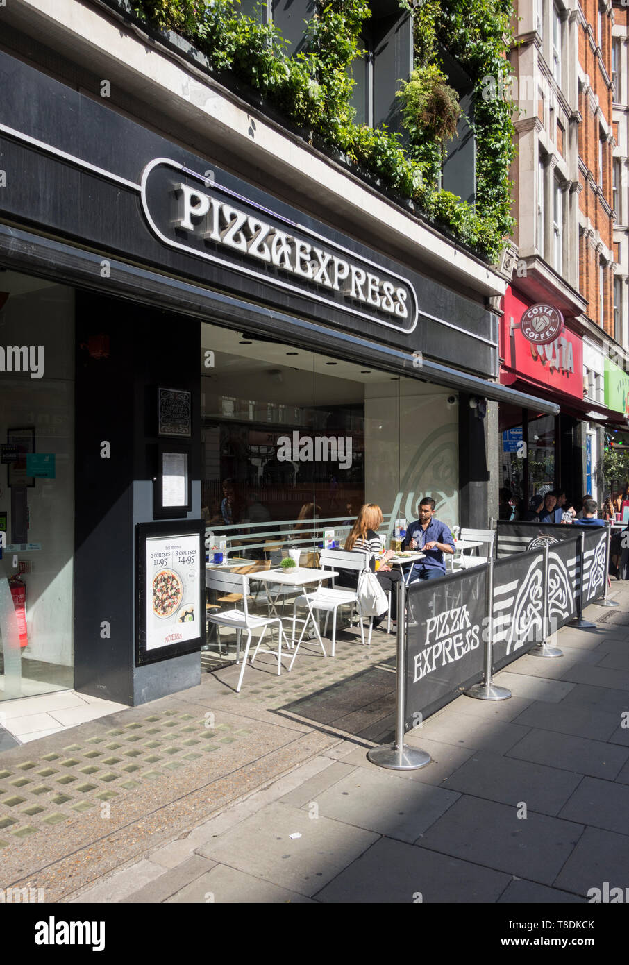 A couple eating outside in the sun at a Pizza Express restaurant on ...