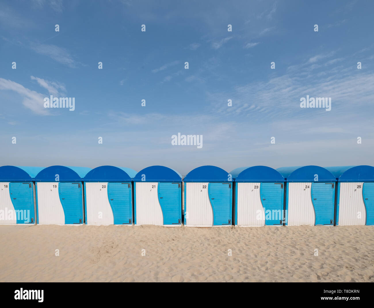 Blue and white striped beach huts on the sand on the sea front at Malo ...