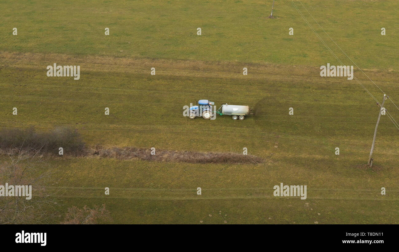 Aerial view of a red tractor and trailer carrying a load of manure on ...