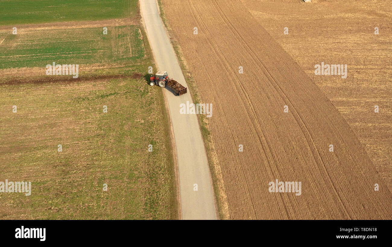 Aerial view of a red tractor and trailer carrying a load of manure on ...
