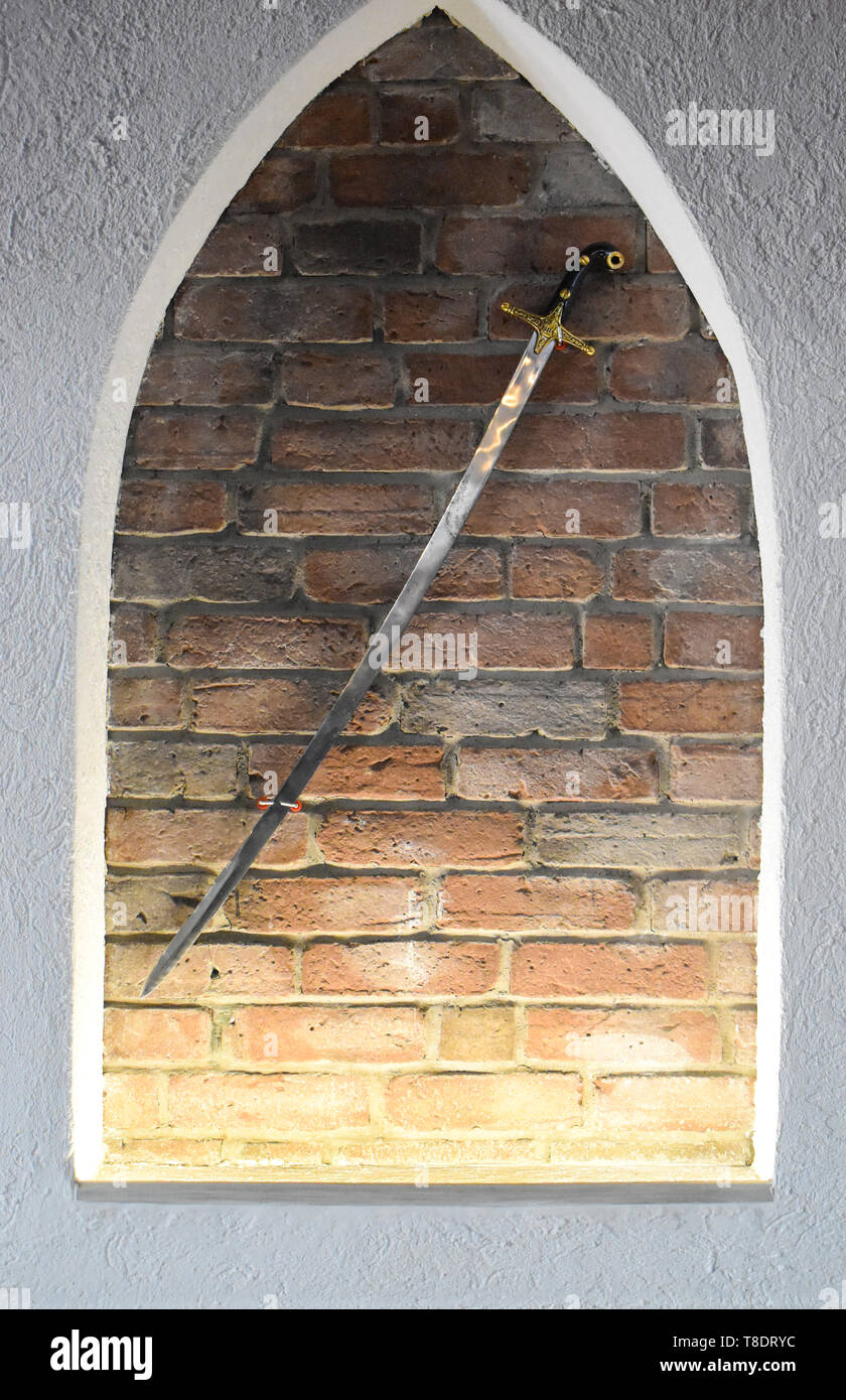 Medieval steel sword against the brick wall background. Ancient shining ...