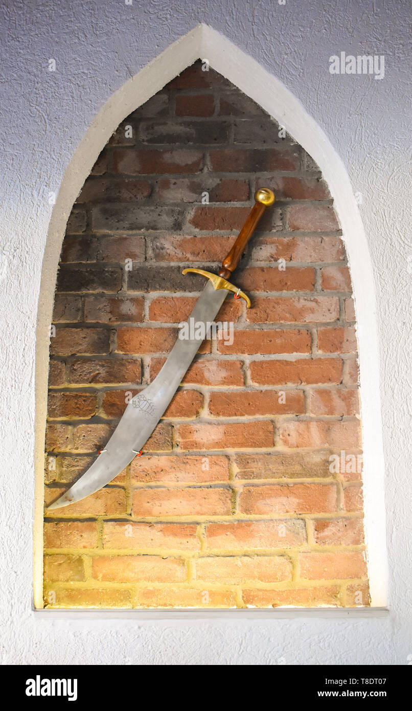 Medieval steel sword against the brick wall background. Ancient shining ...