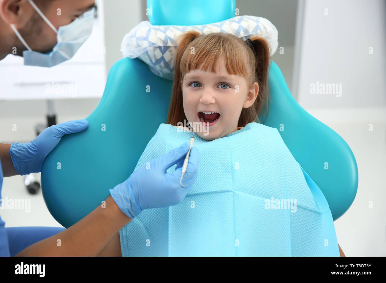 Dentist examining little girl's teeth in clinic Stock Photo - Alamy