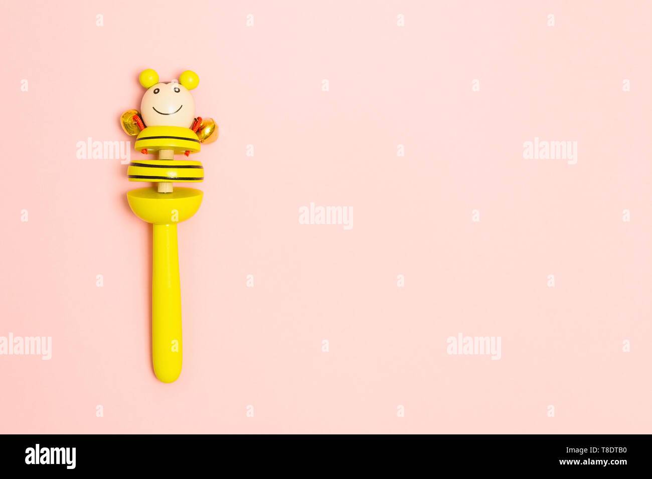 Yellow wooden baby toy with bells. Traditional rattle on pink ...