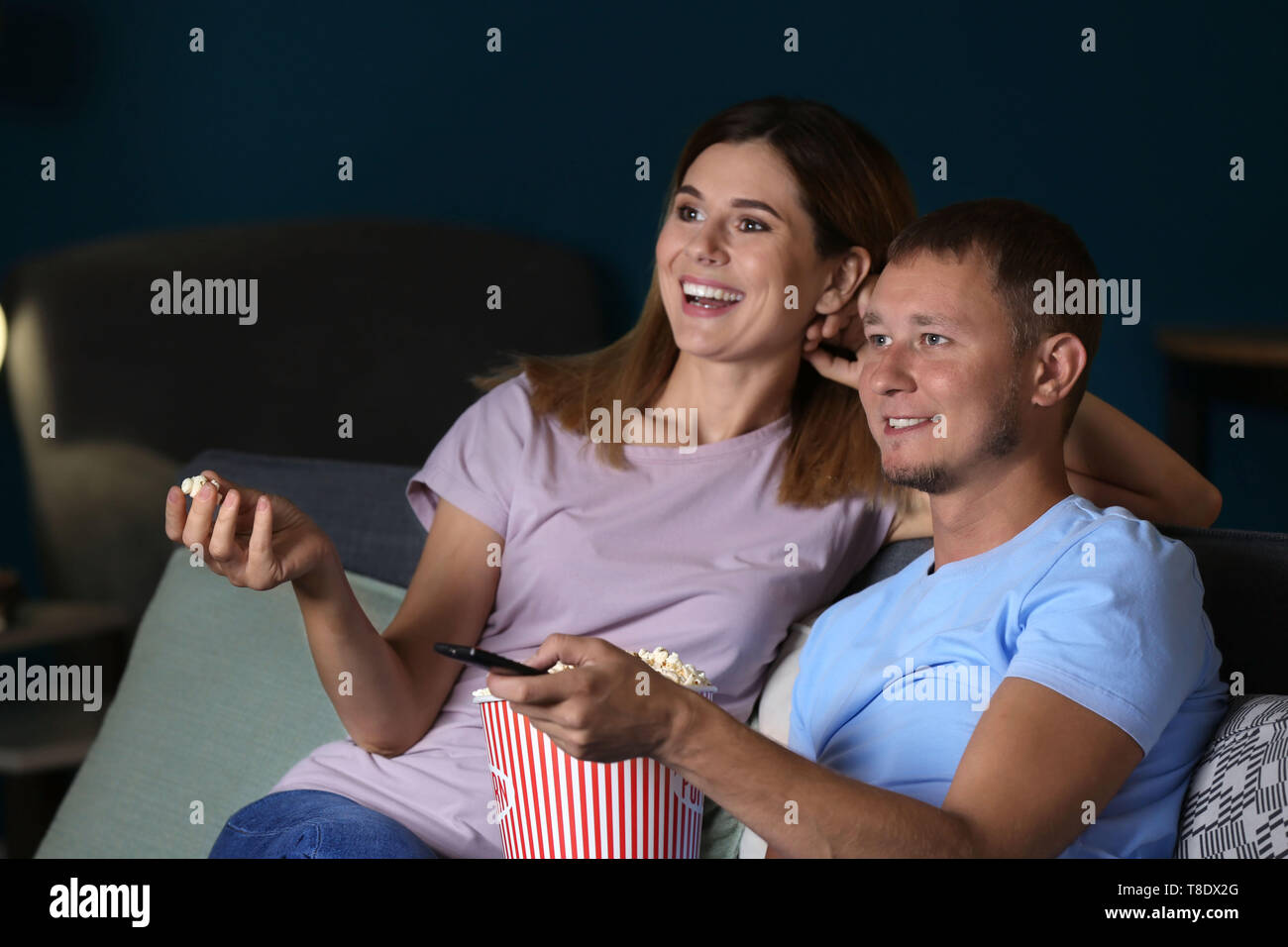 Couple eating popcorn while watching TV in evening Stock Photo - Alamy
