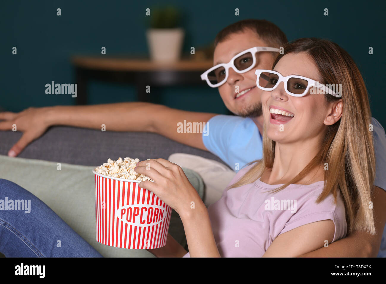 Couple eating popcorn while watching TV in evening Stock Photo - Alamy