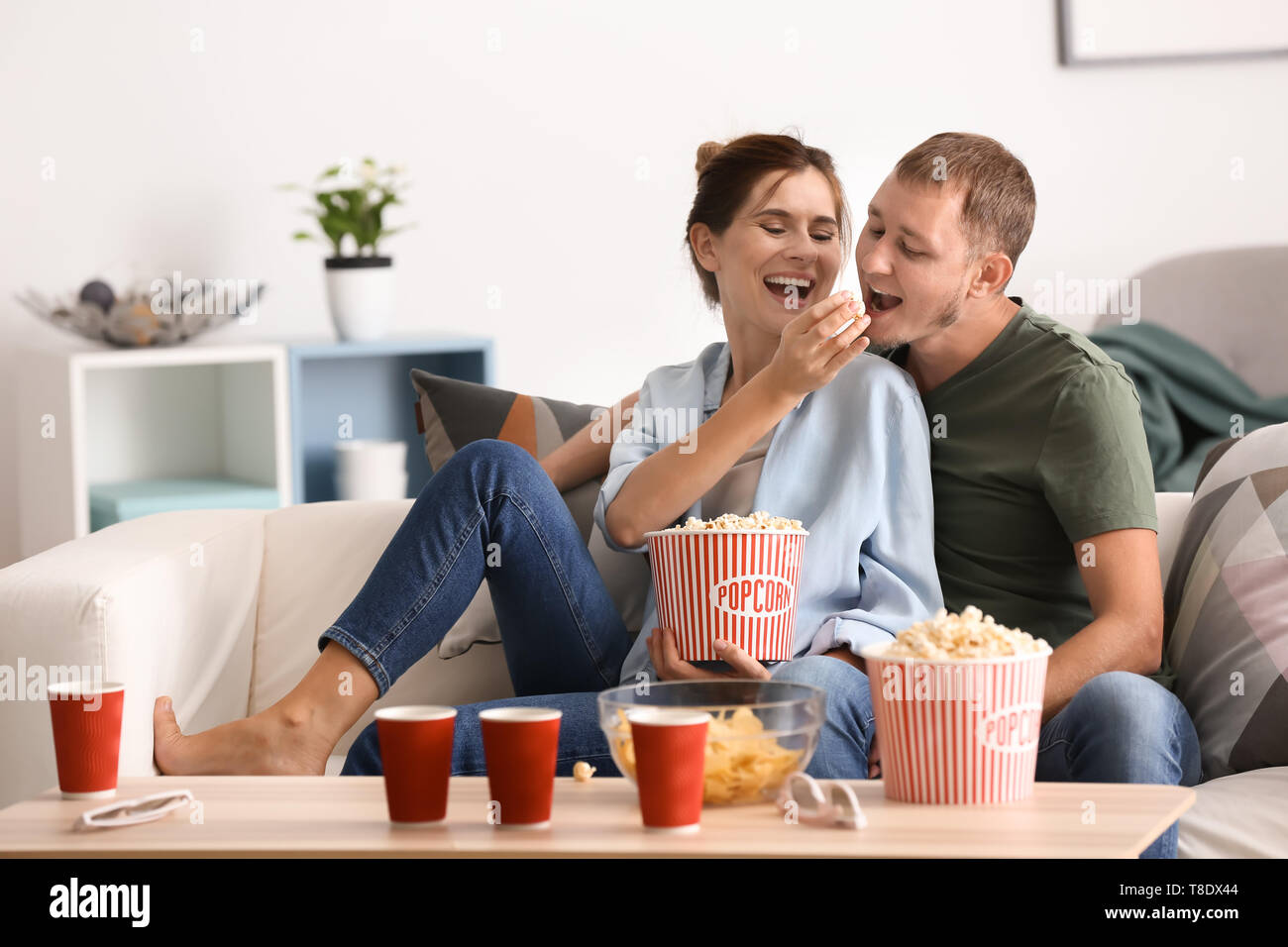 Couple eating popcorn while watching TV at home Stock Photo - Alamy