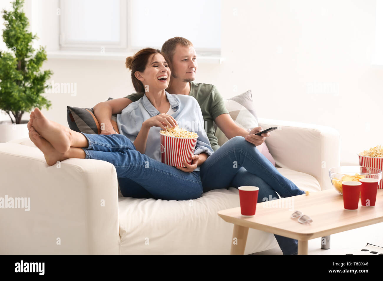 Couple eating popcorn while watching TV at home Stock Photo - Alamy
