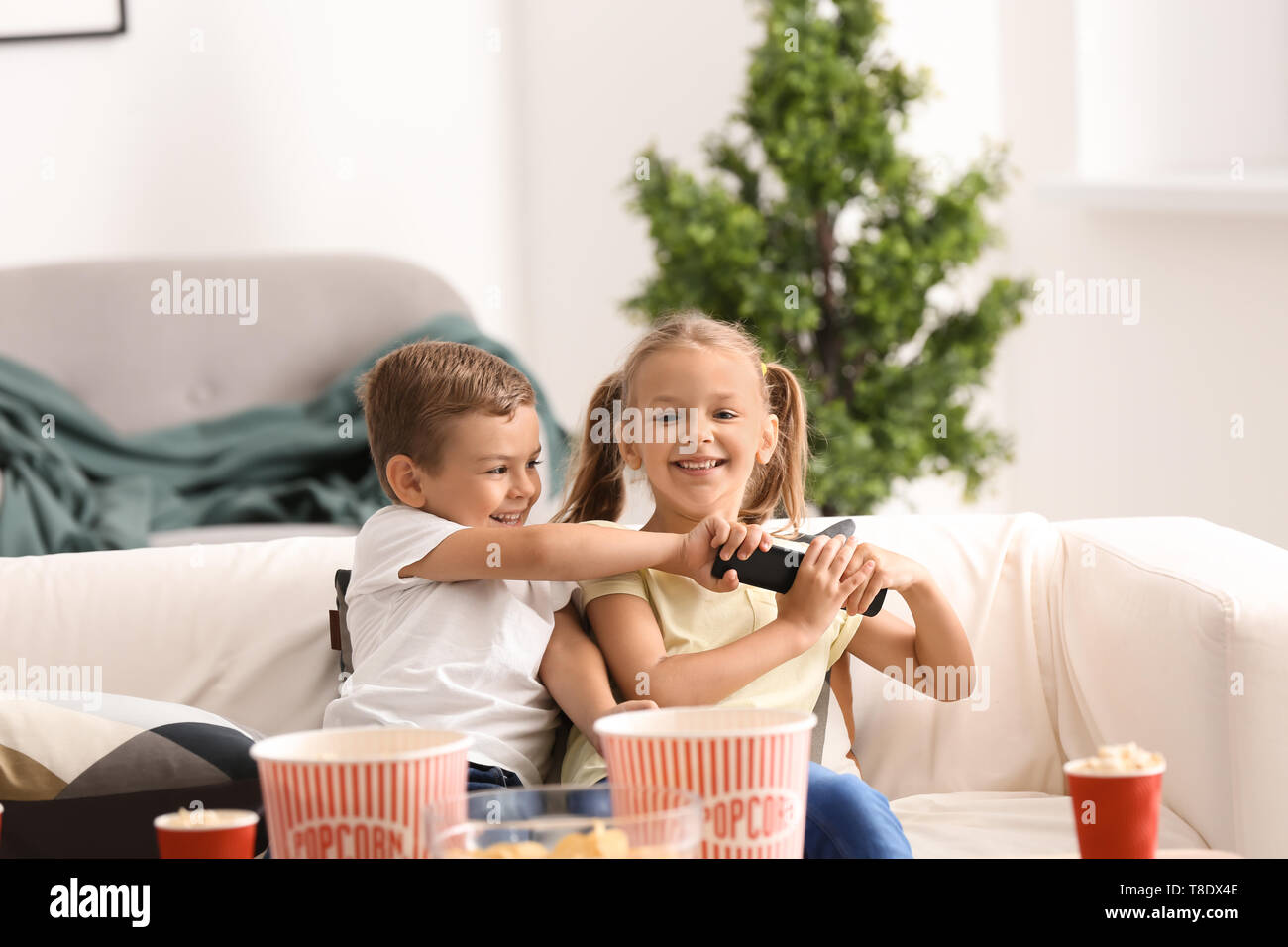 Children fighting for remote control while watching TV at home Stock ...