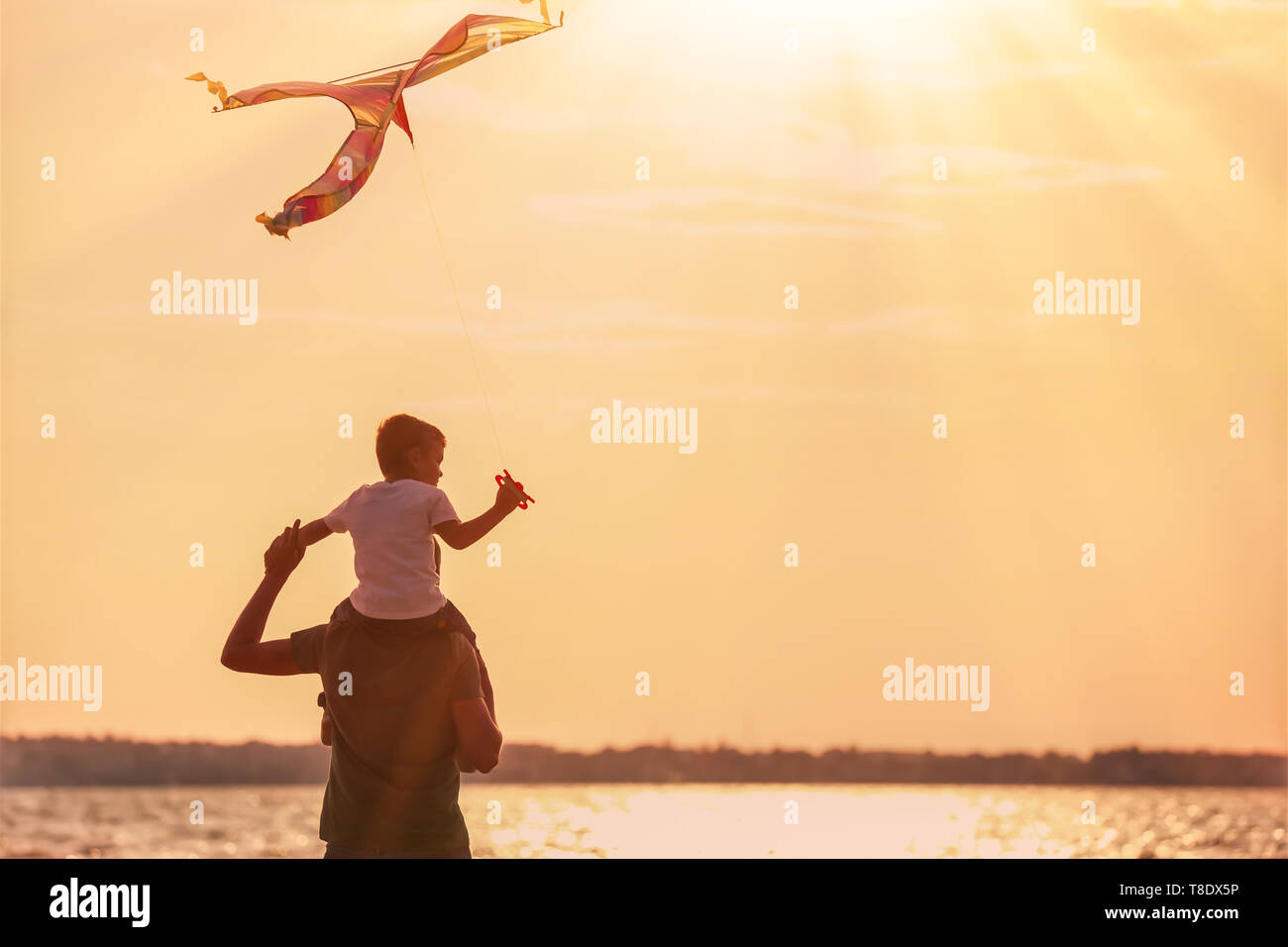 Happy father and son flying kite near river at sunset Stock Photo - Alamy