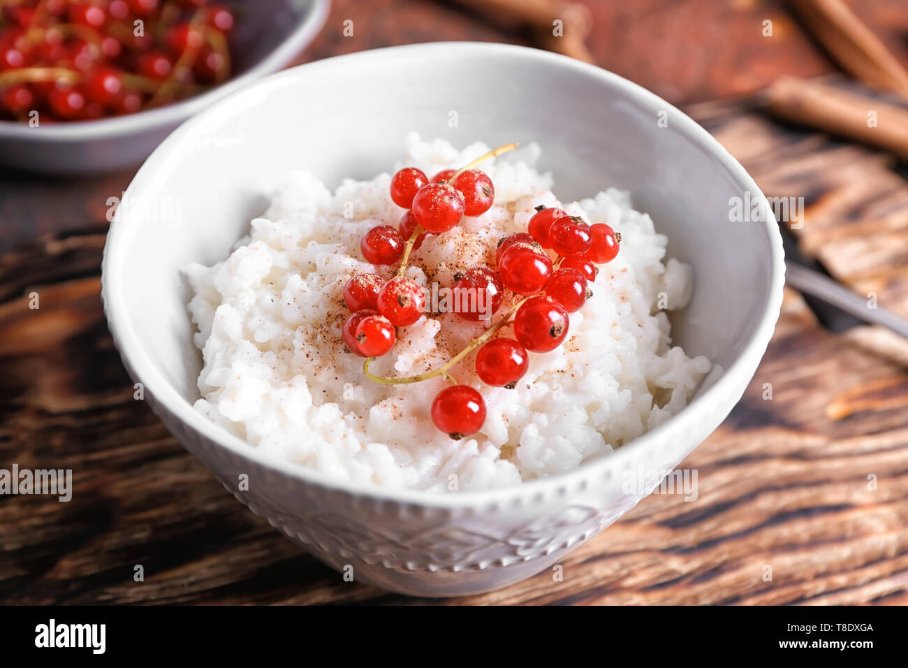 Bowl with delicious rice pudding and currants on wooden table, closeup ...
