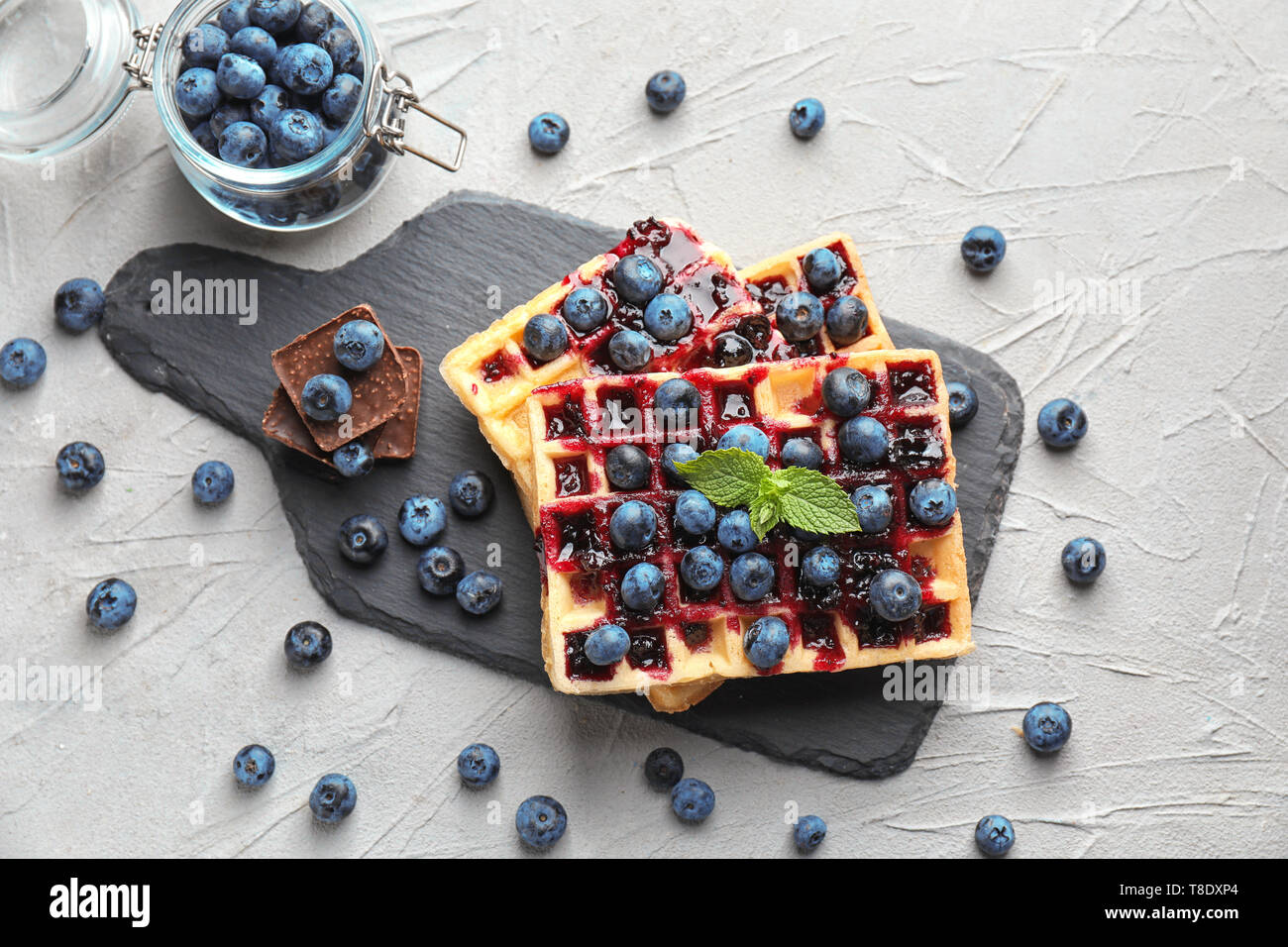 Delicious waffles with blueberries and jam on slate plate Stock Photo ...