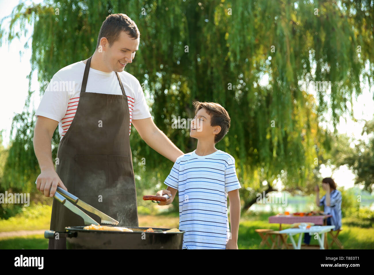 Little boy with his father cooking tasty food on barbecue grill ...