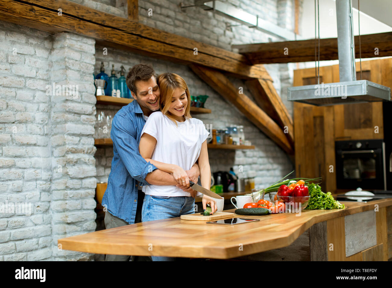Lovely cheerful young couple cooking dinner together and having fun at ...