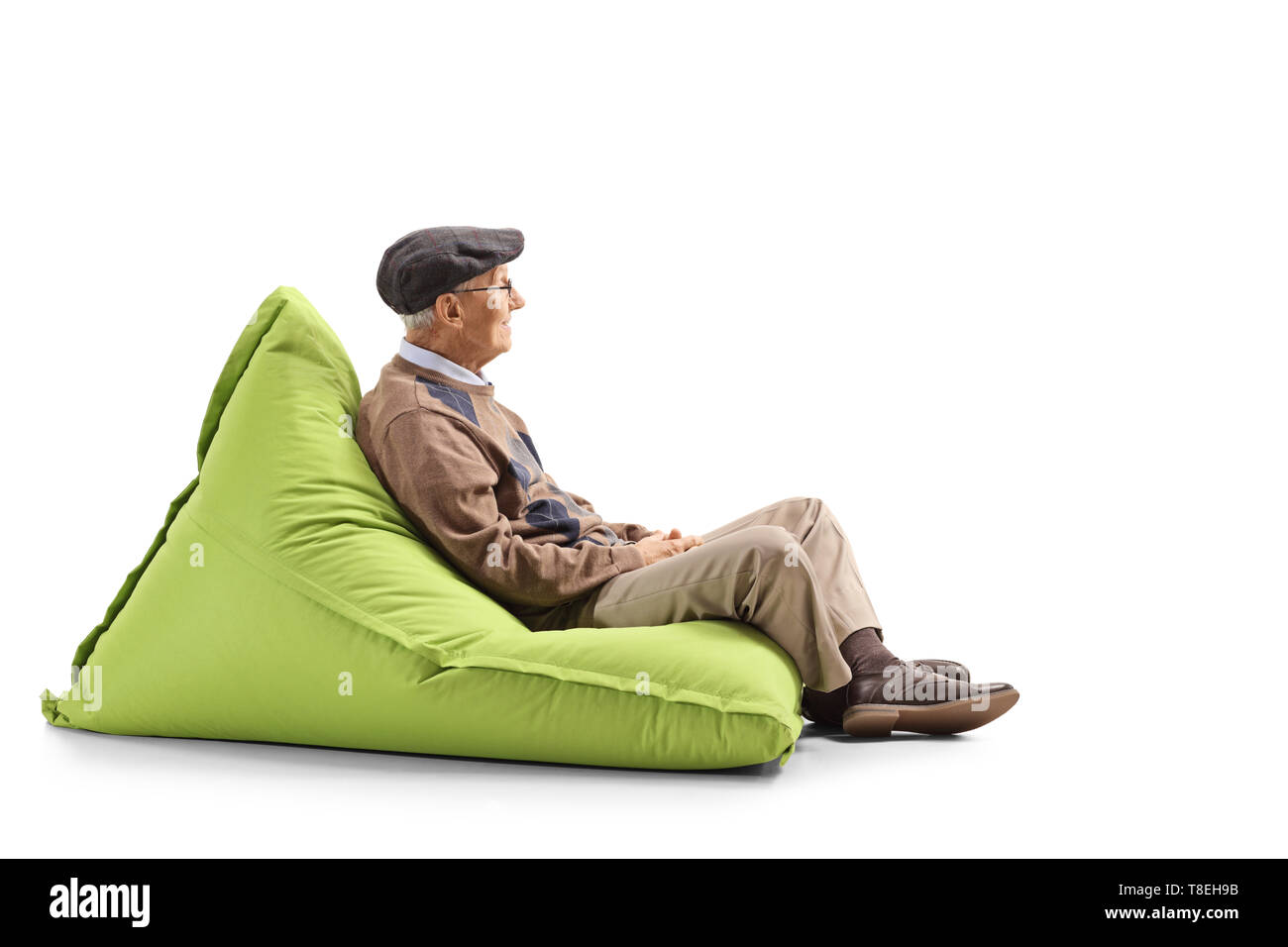 Full length profile shot of an elderly man sitting on a green bean bag ...