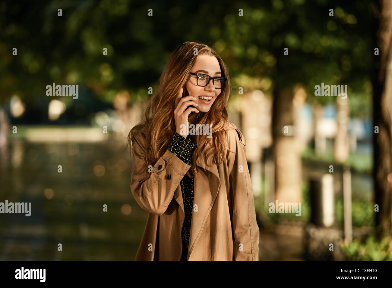 Portrait of beautiful woman 20s wearing coat and eyeglasses using cell ...