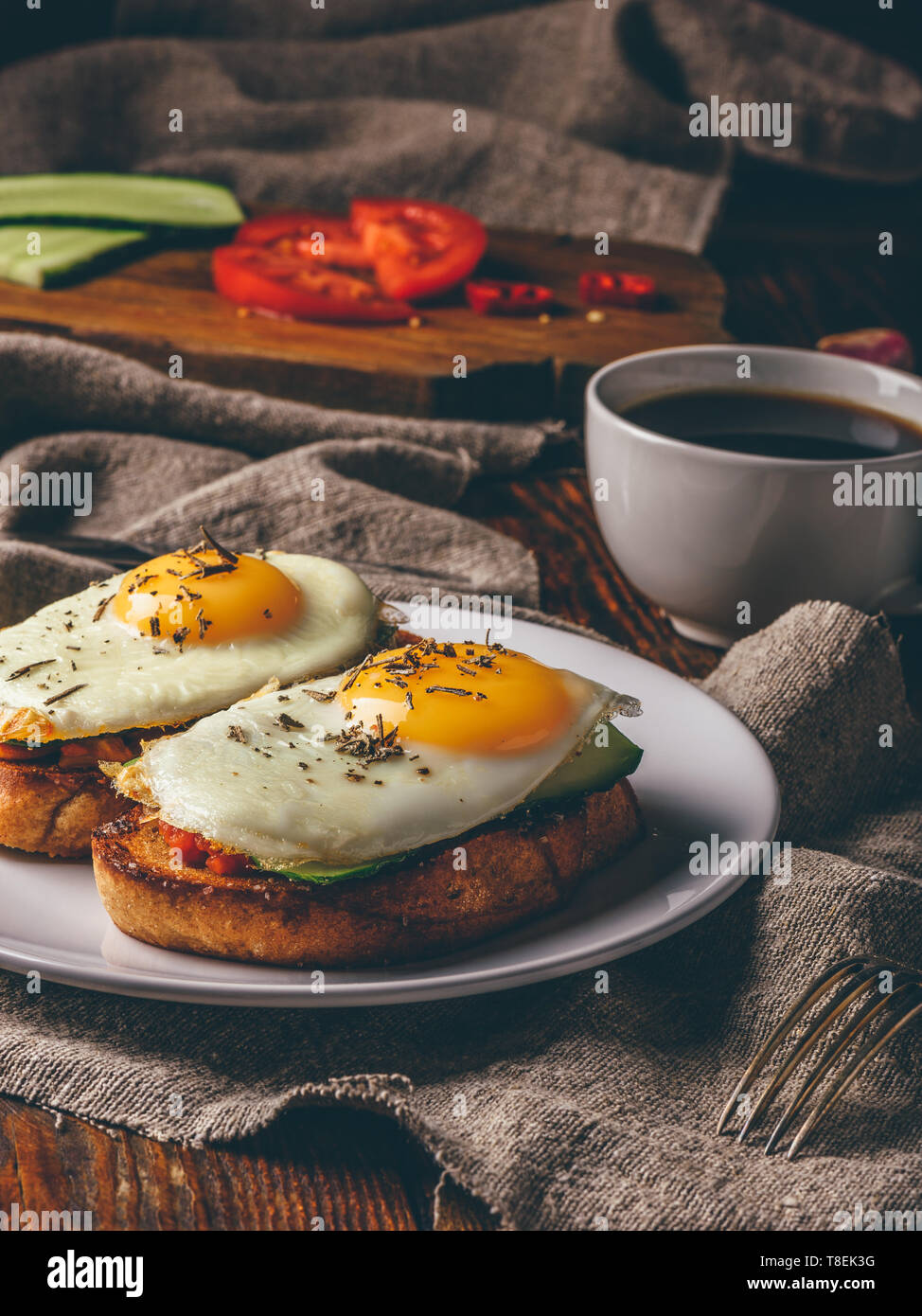 Italian toasts with vegetables and fried eggs on white plate and cup of ...