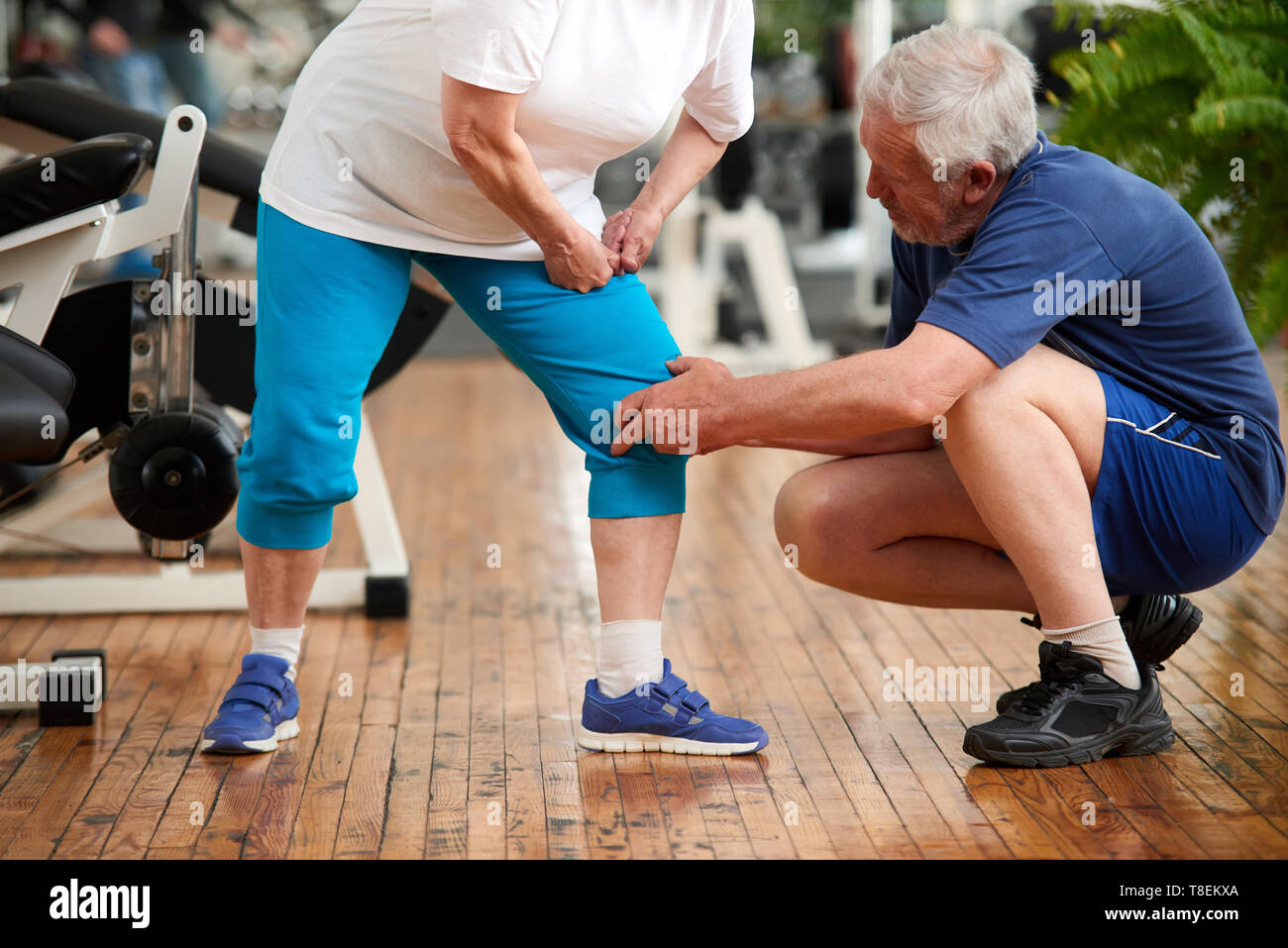 Injured senior woman at gym. Husband helping his injured wife at sporrt ...