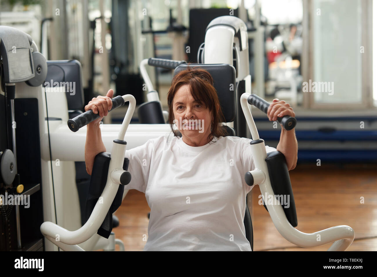 Mature woman working out at gym. Pretty woman exercising using chest ...