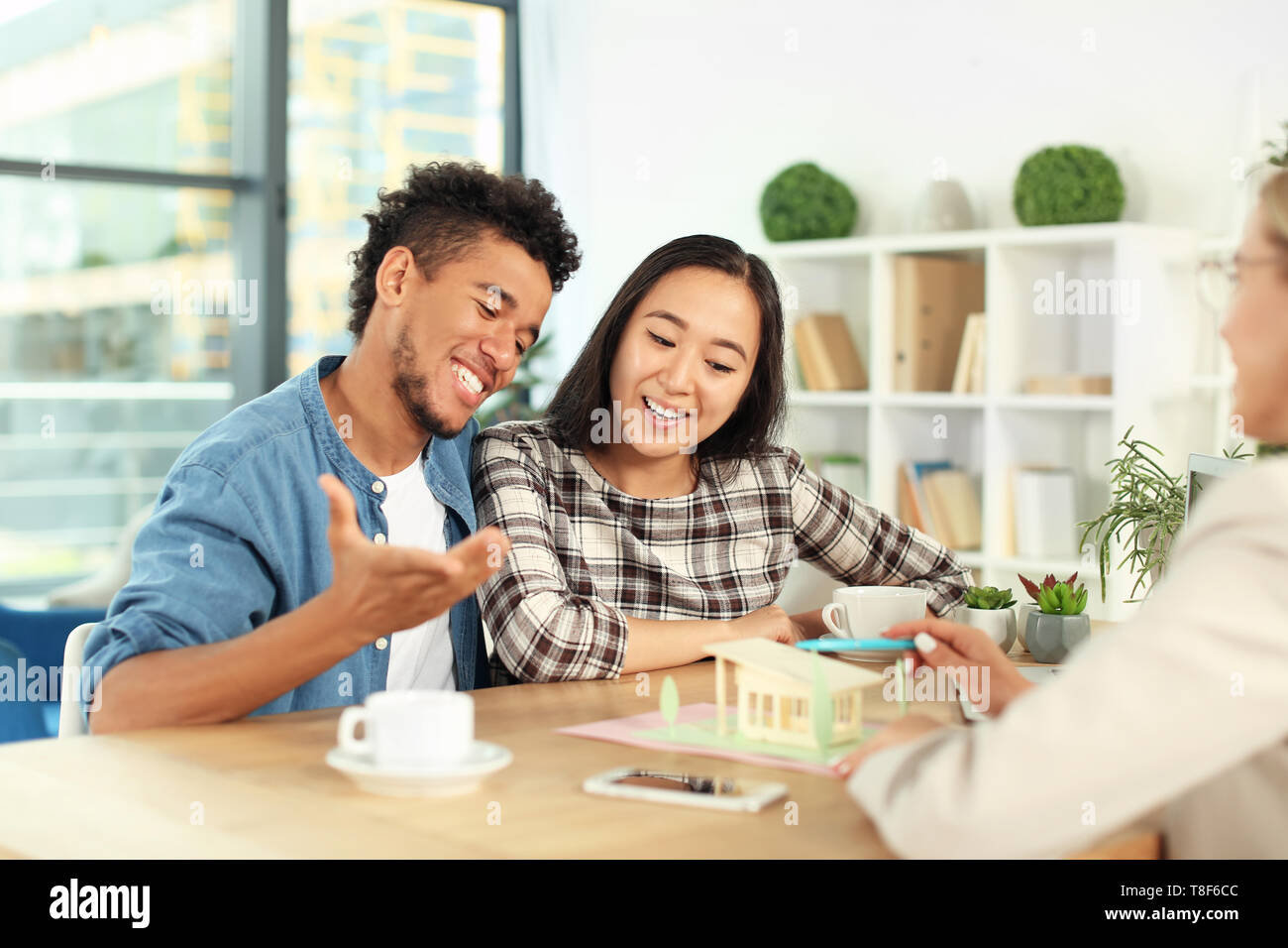 Real estate agent showing model of house to clients in her office Stock ...