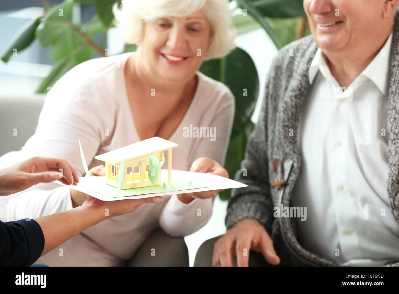 Real estate agent showing model of house to clients in her office Stock ...