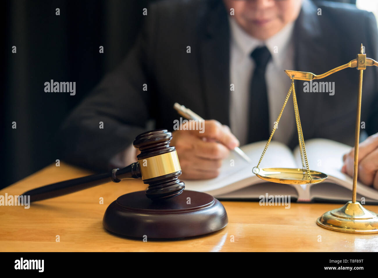 Male lawyer working with contract papers and reading law book in a ...