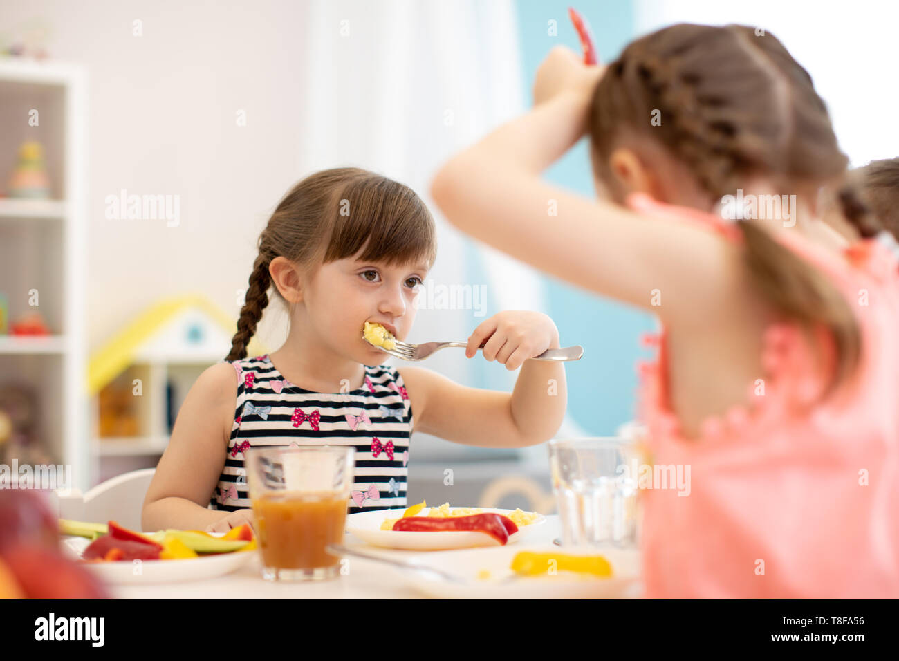 Kids have lunch in daycare, kindergarten or home. Child girl eating ...