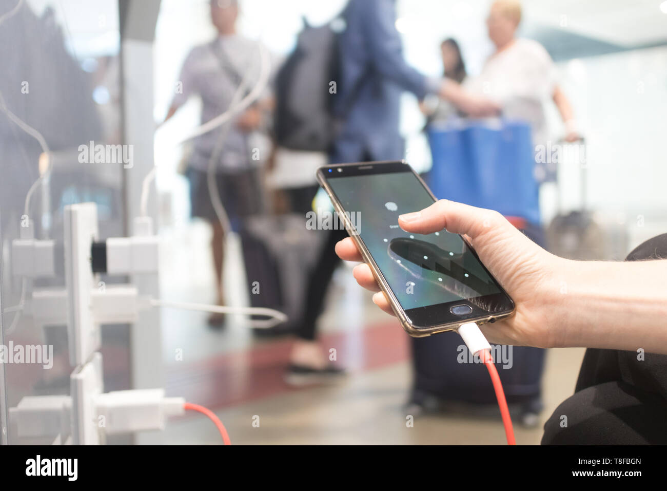 Female hands holding and using smartphone while charging it in a public ...