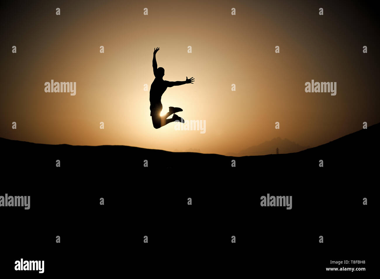 success, freedom, energy concept. Man jump on sunset sky background ...