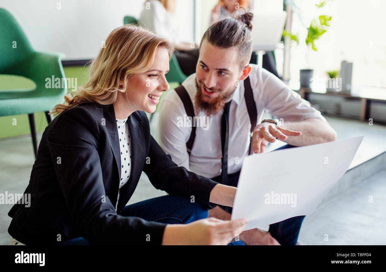Two business people looking at paper documents in an office, talking ...