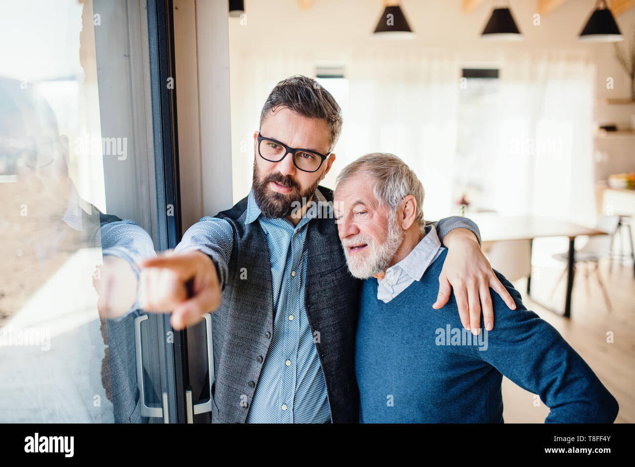 A Portrait Of Adult Hipster Son And Senior Father Indoors At Home