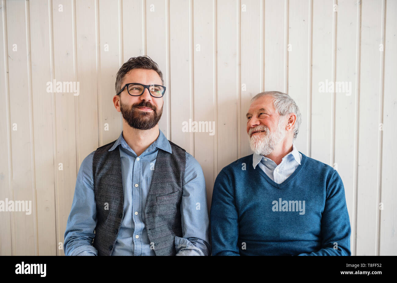 A Portrait Of Adult Hipster Son And Senior Father Sitting On Floor
