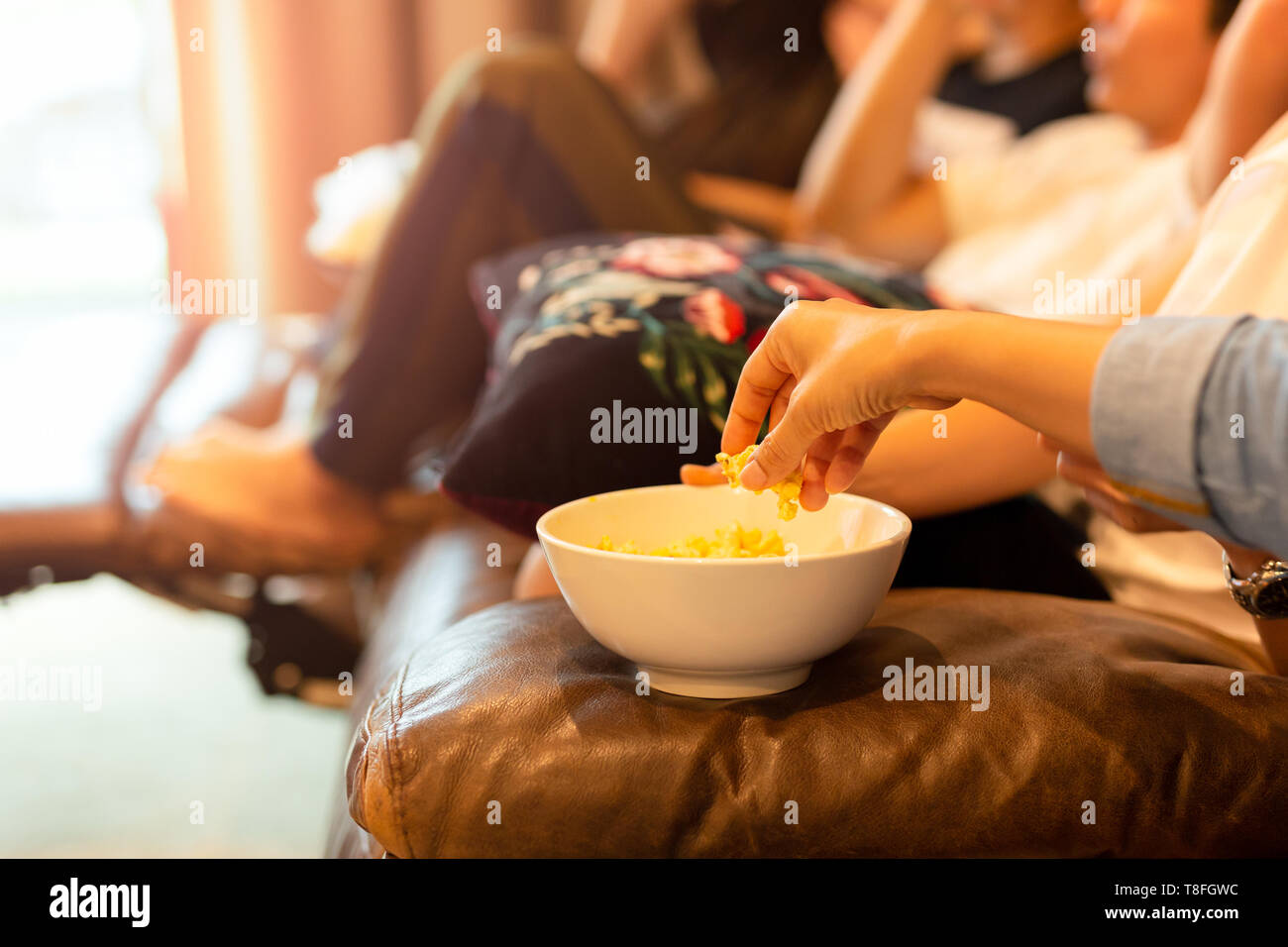Hands taking popcorn from bowl watching movie with friends Stock Photo ...