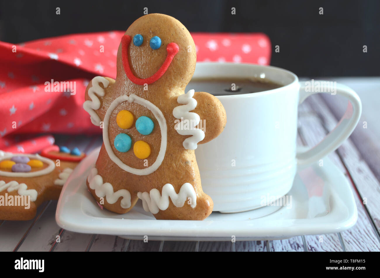White cup of tea with a gingerbread man cookie, another gingerbread man ...