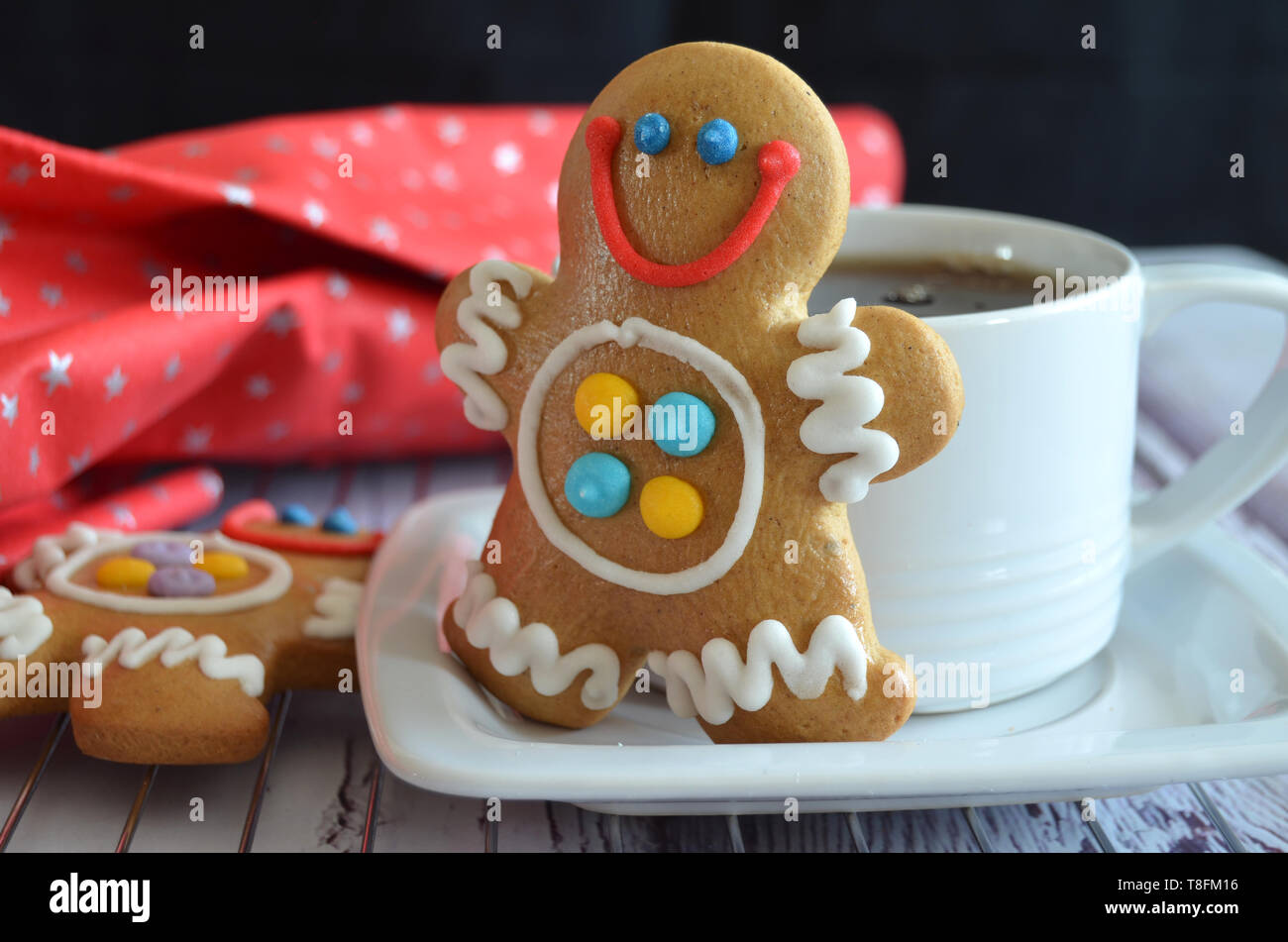 White cup of tea with a gingerbread man cookie, another gingerbread man ...