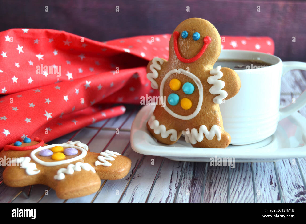 White cup of tea with a gingerbread man cookie, another gingerbread man ...